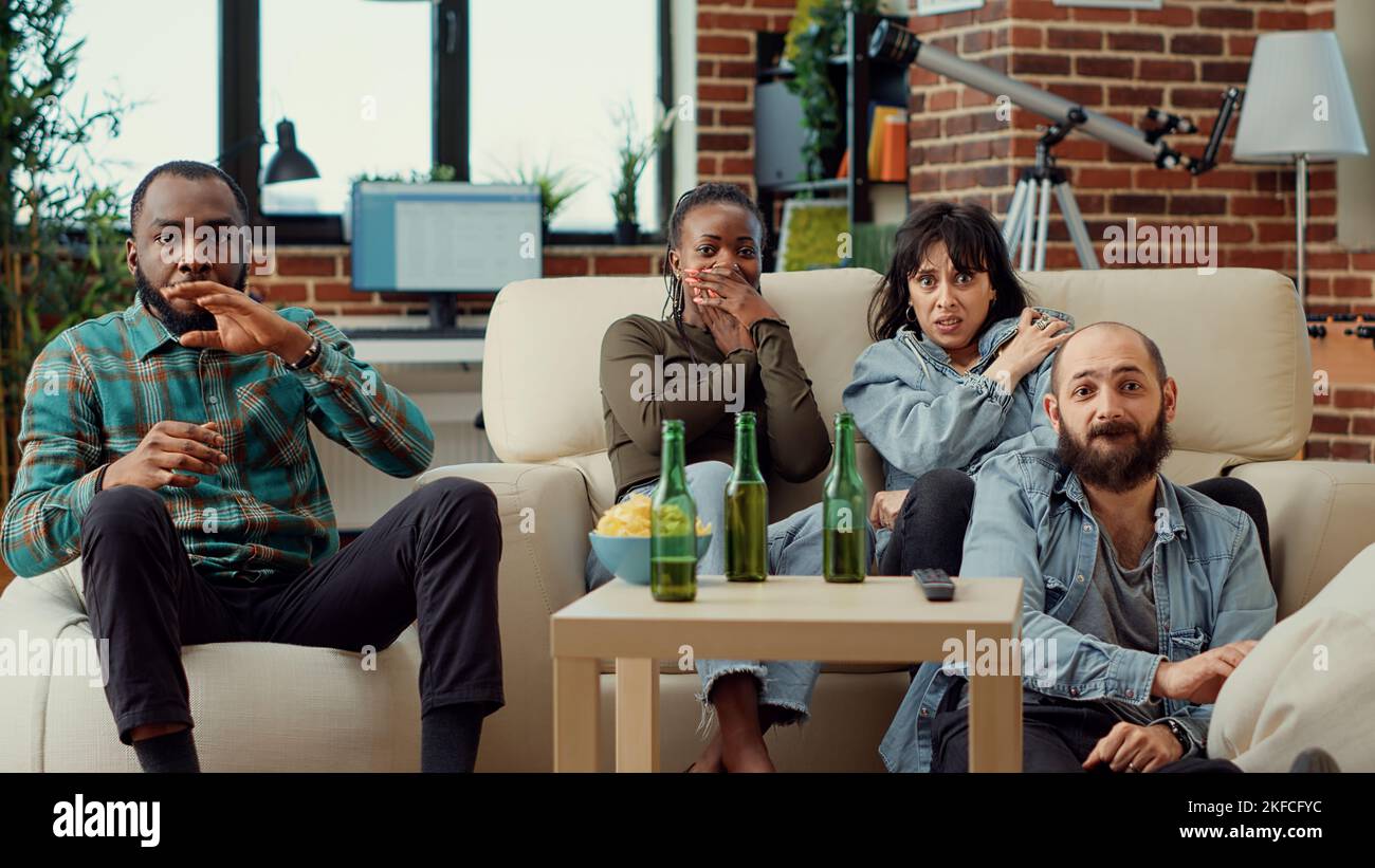 Terrified group of friends watching horror movie on television, getting ...