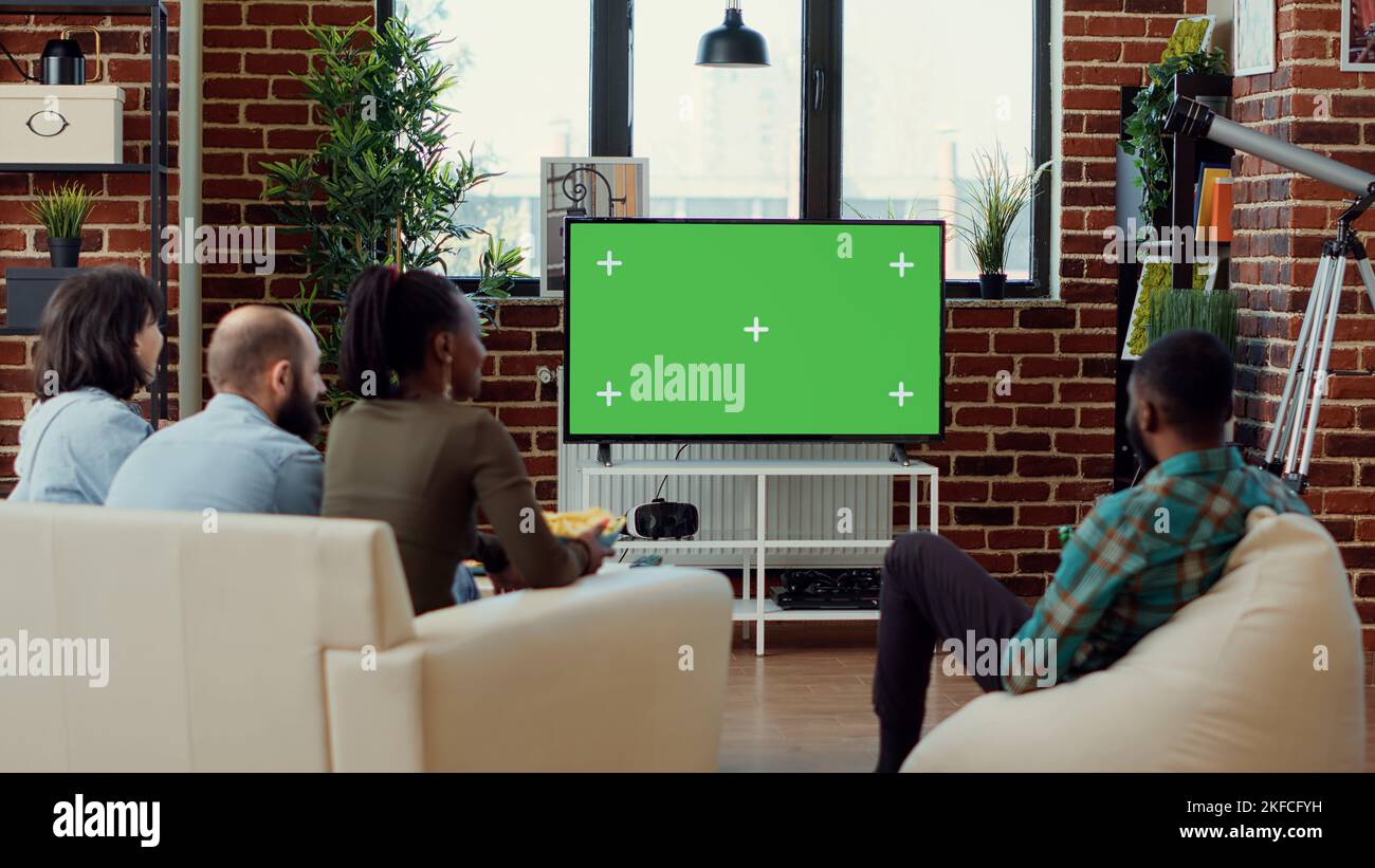 Multiethnic group of people enjoying tv show on greenscreen, watching ...