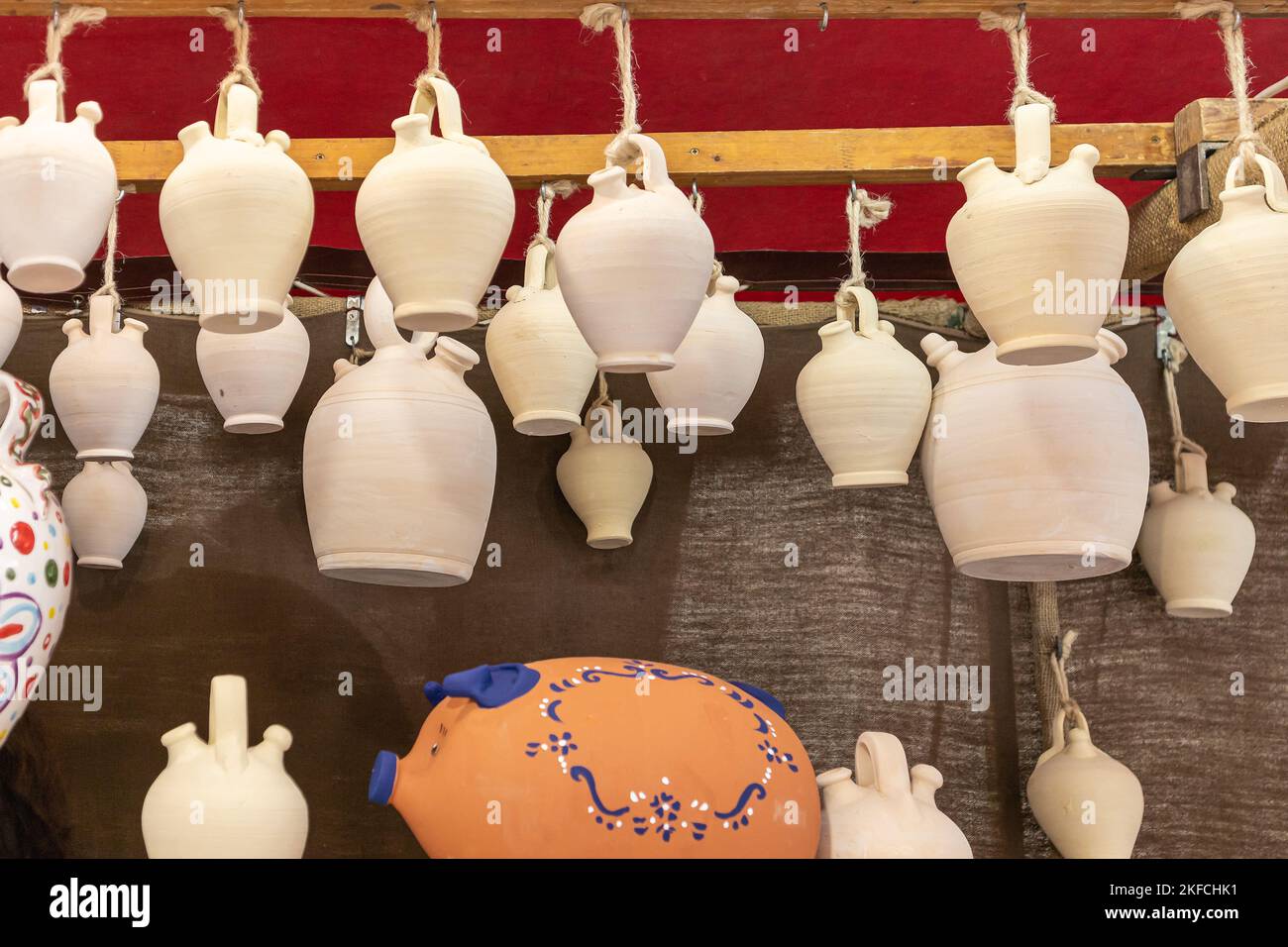 close up in horizontal view of several white botijos of clay hanging ...