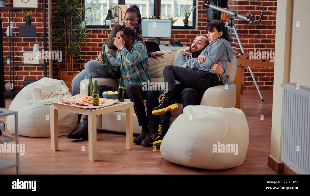 Multiethnic group of friends having terrified reaction while they watch ...