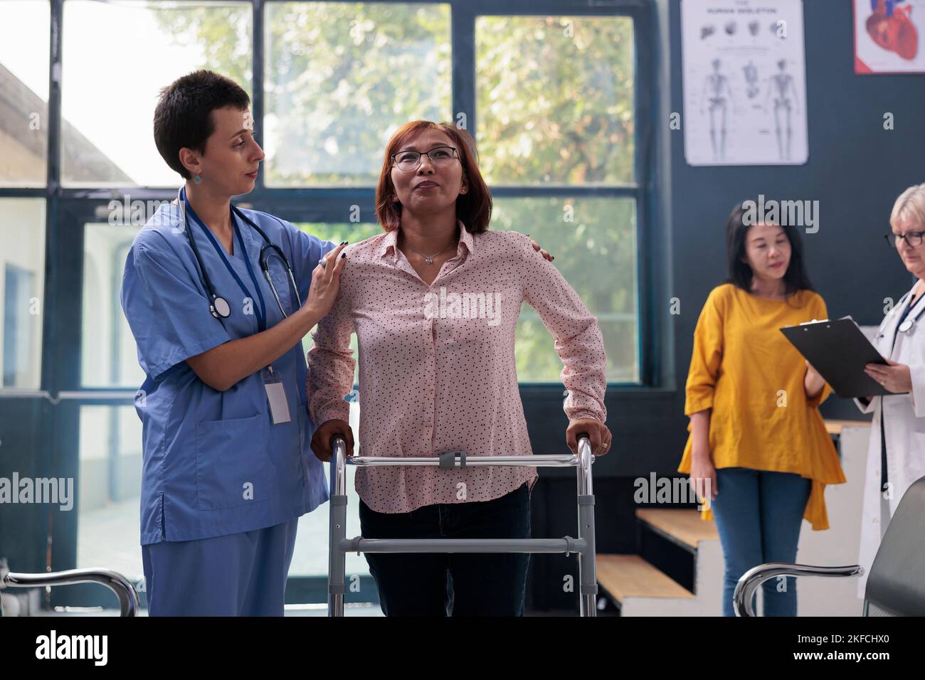 Medical assistant helping asian patient to walk with walking frame ...