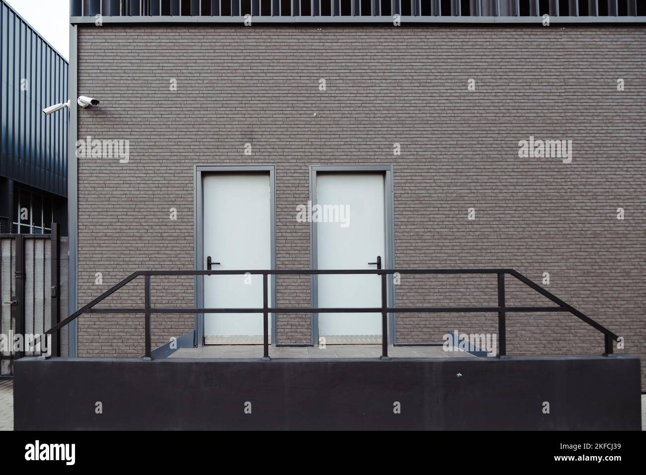 Modern industrial facade with emergency exit doors and stairs, cctv ...