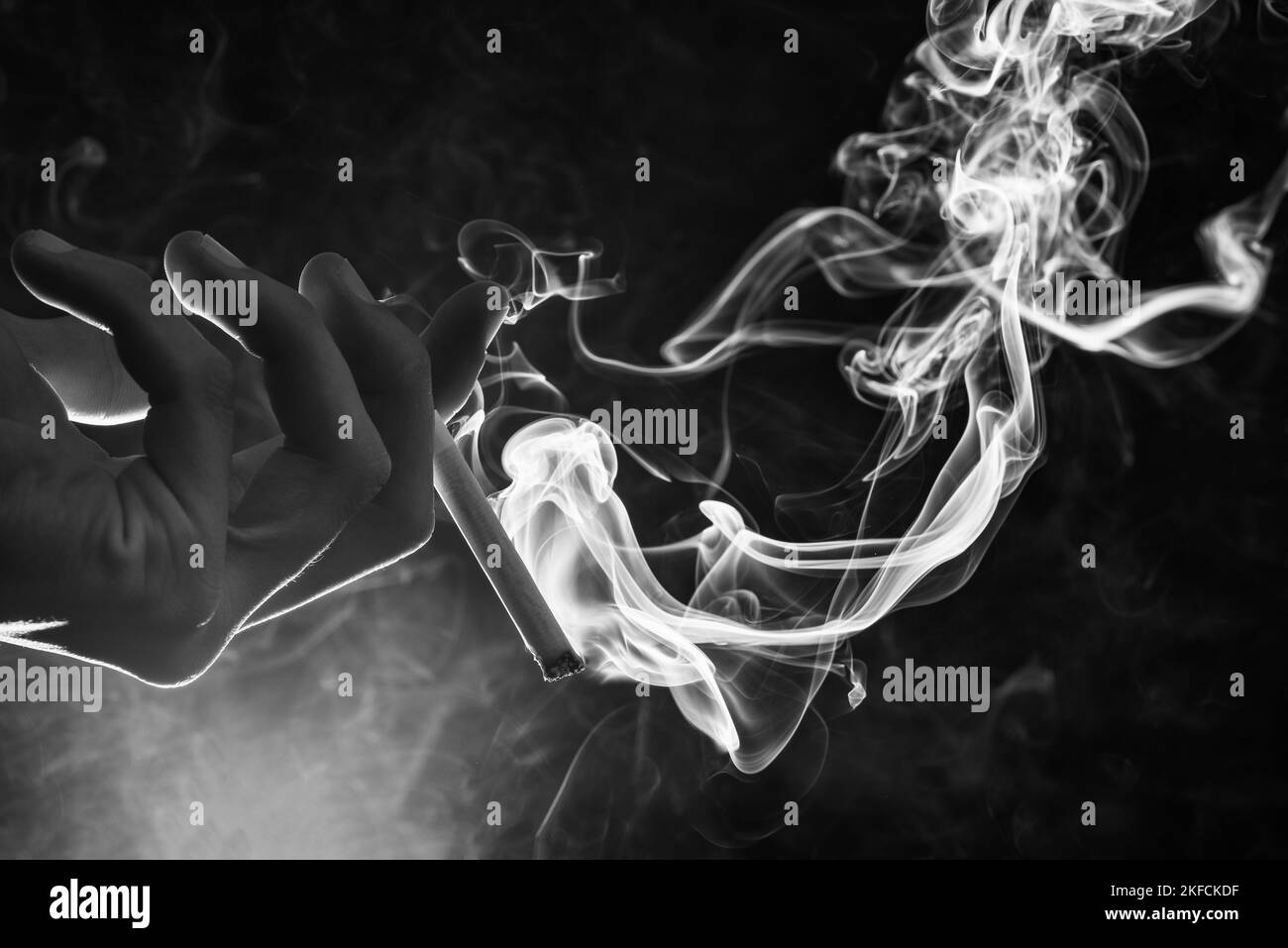 Male hand hold burning cigarette with swirl of smoke dark background ...