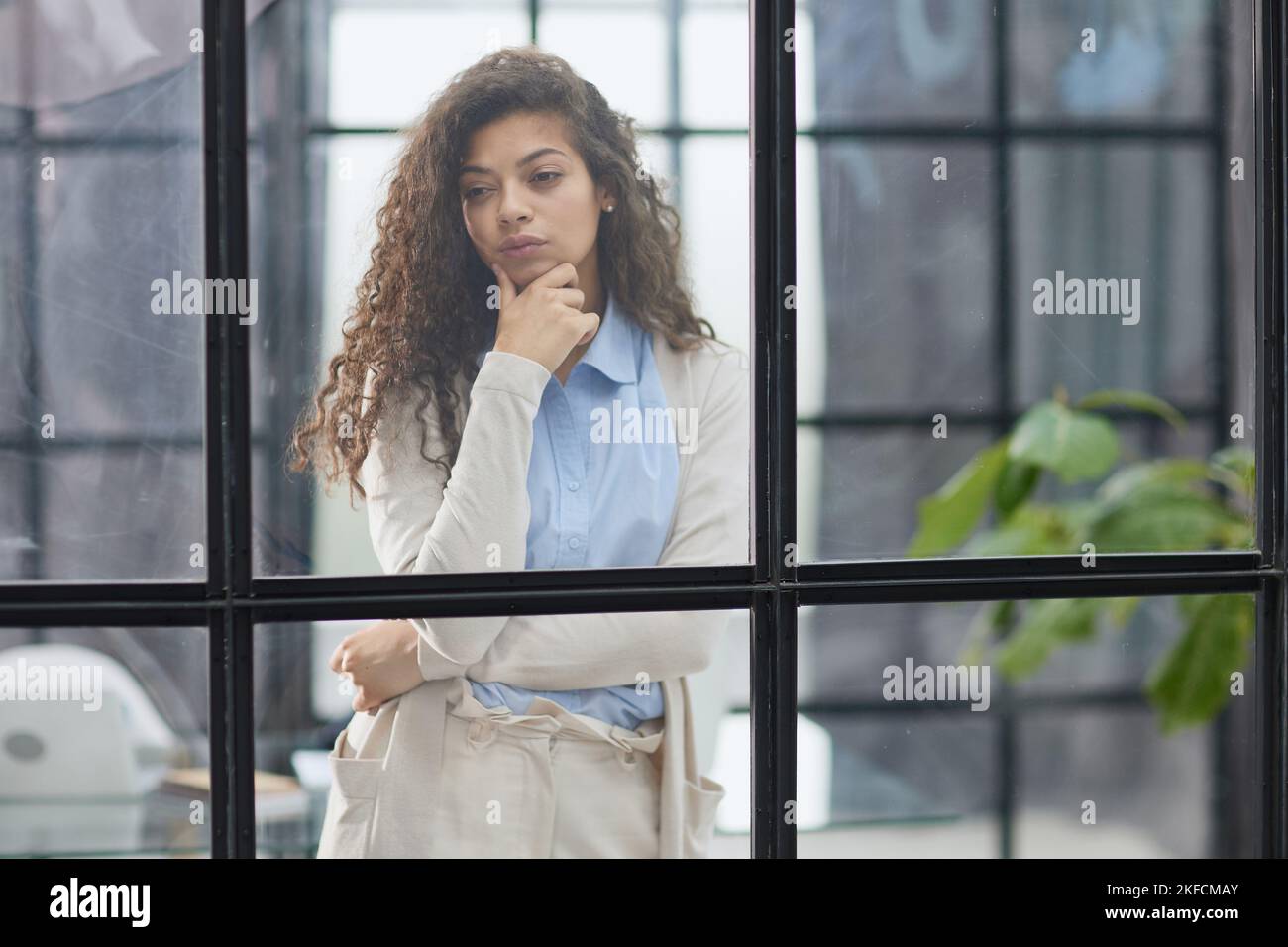 from behind the glass. young business woman thinking about something ...