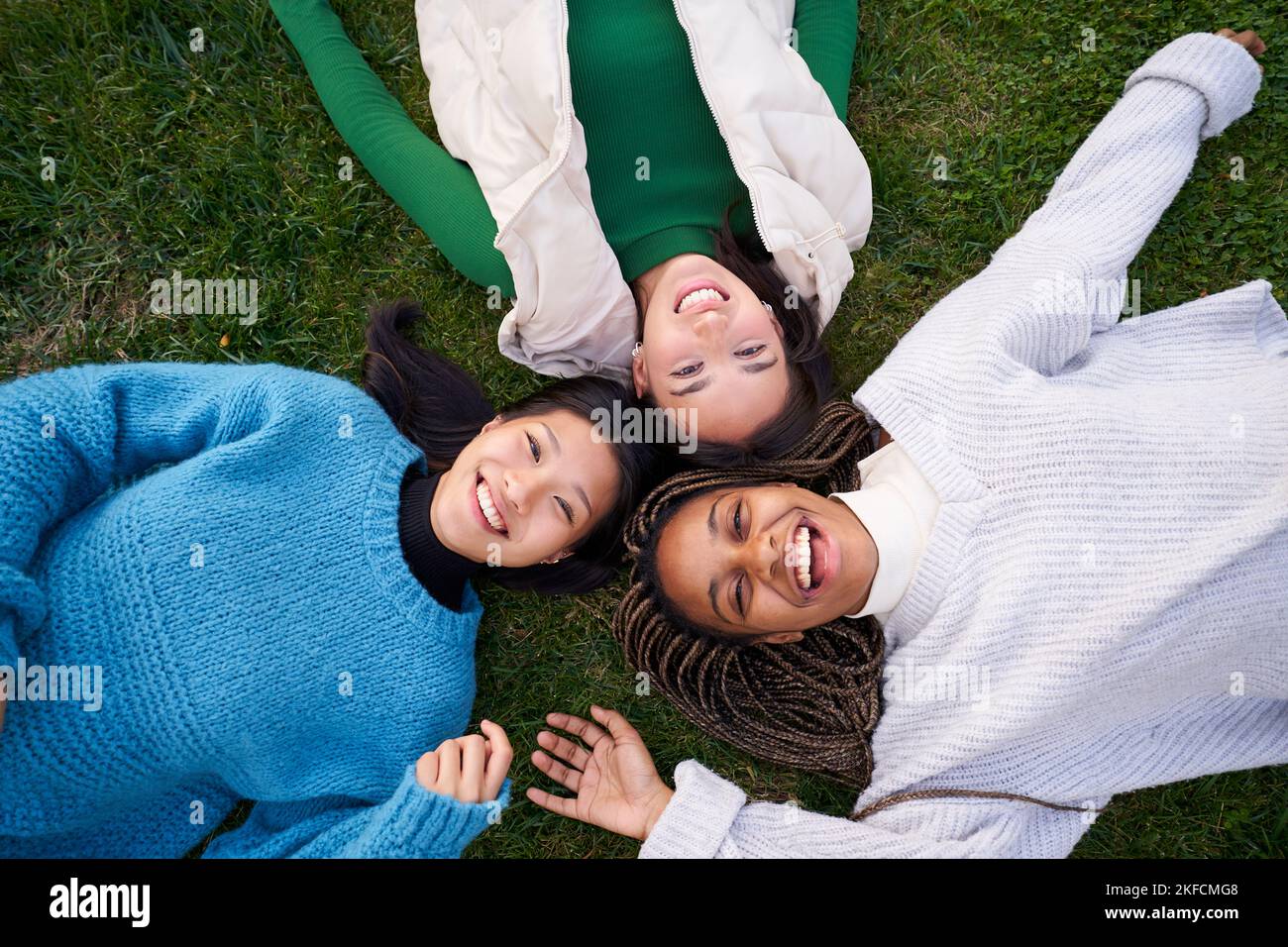 Joyful portrait of three best friends lying on grass having good time ...
