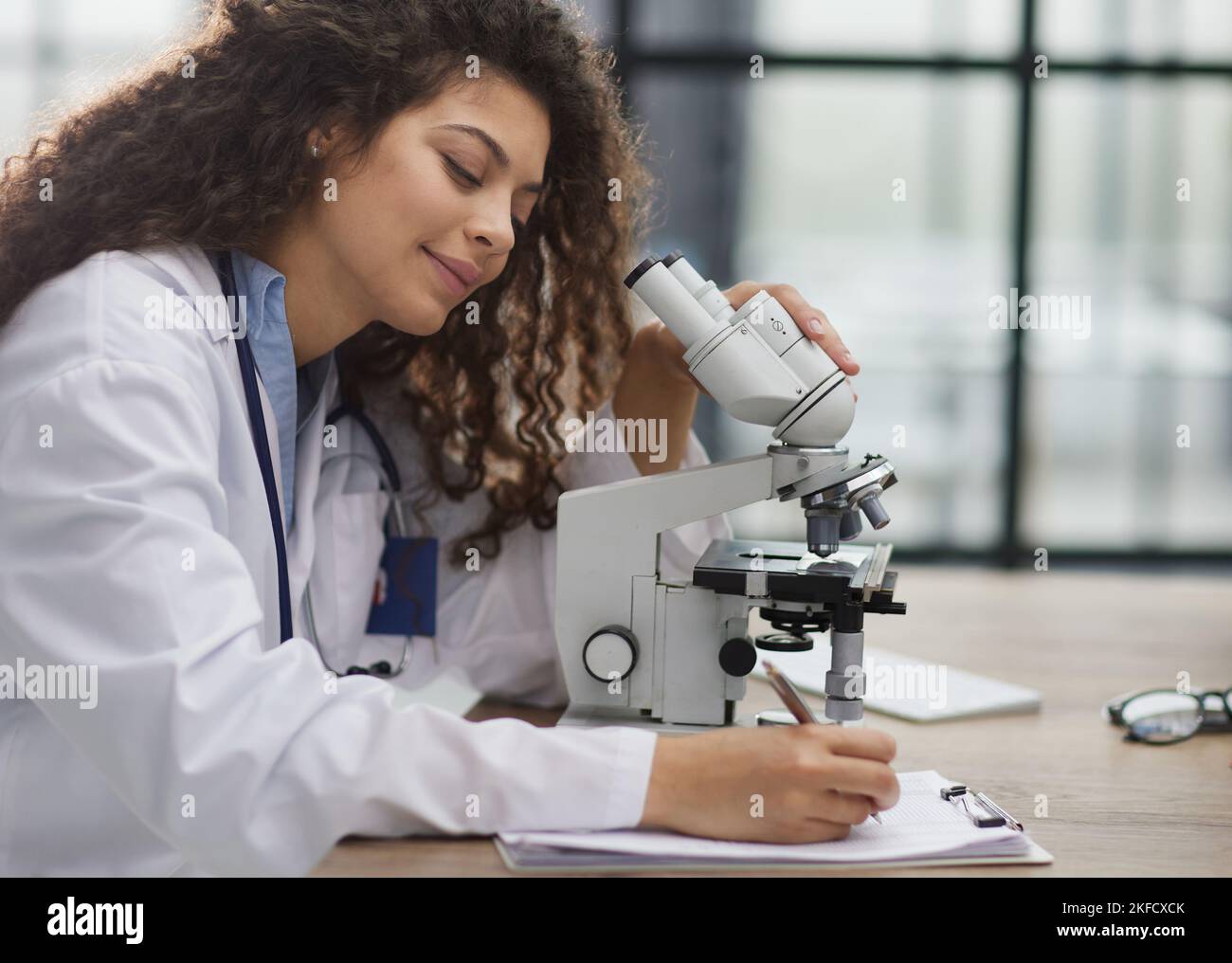 Attractive female scientist looking through a microscope Stock Photo ...