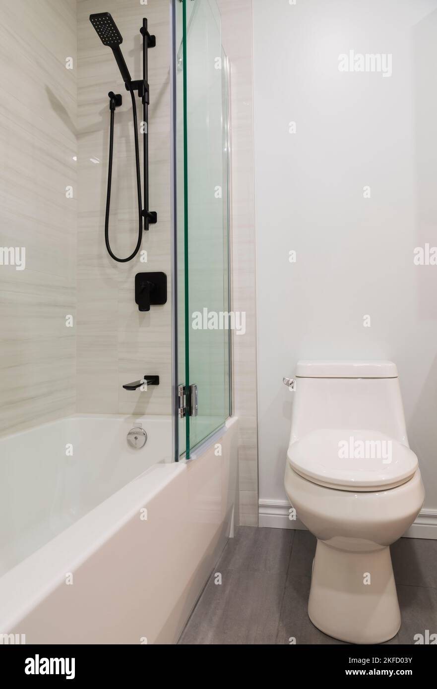 Bathtub with glass shower panels and toilet in bathroom inside ...