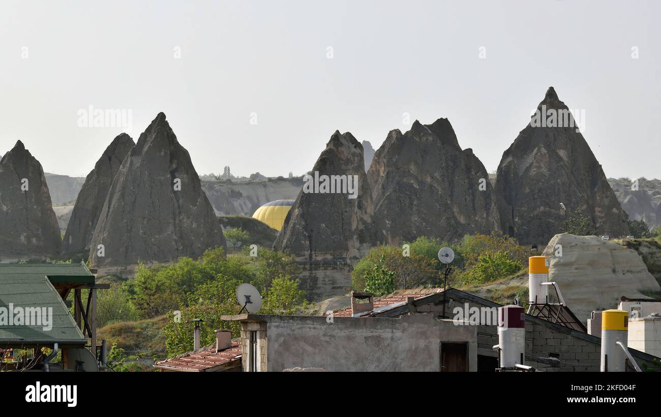 The Fairy Chimneys rock formations behind buildings at Goreme National ...