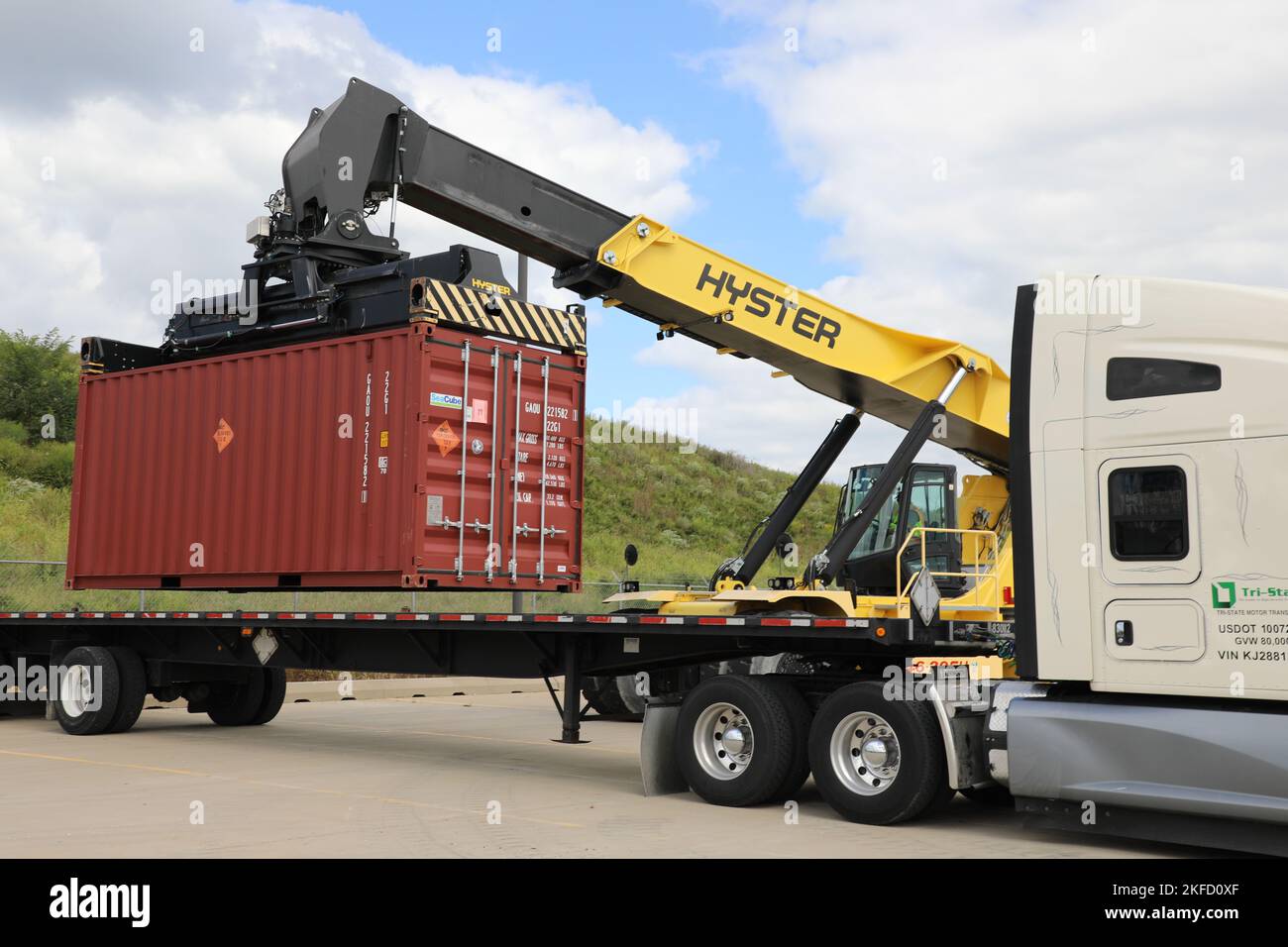 Hyster operator places a container onto a semi truck for distribution ...