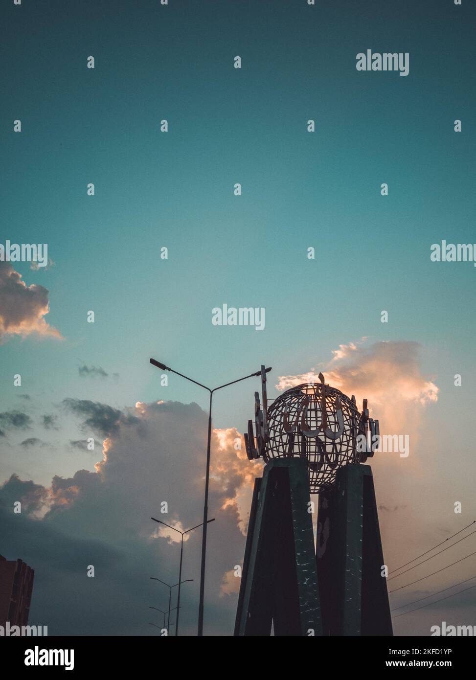 A vertical shot of a metallic sphere with "Allah" written. monument in ...