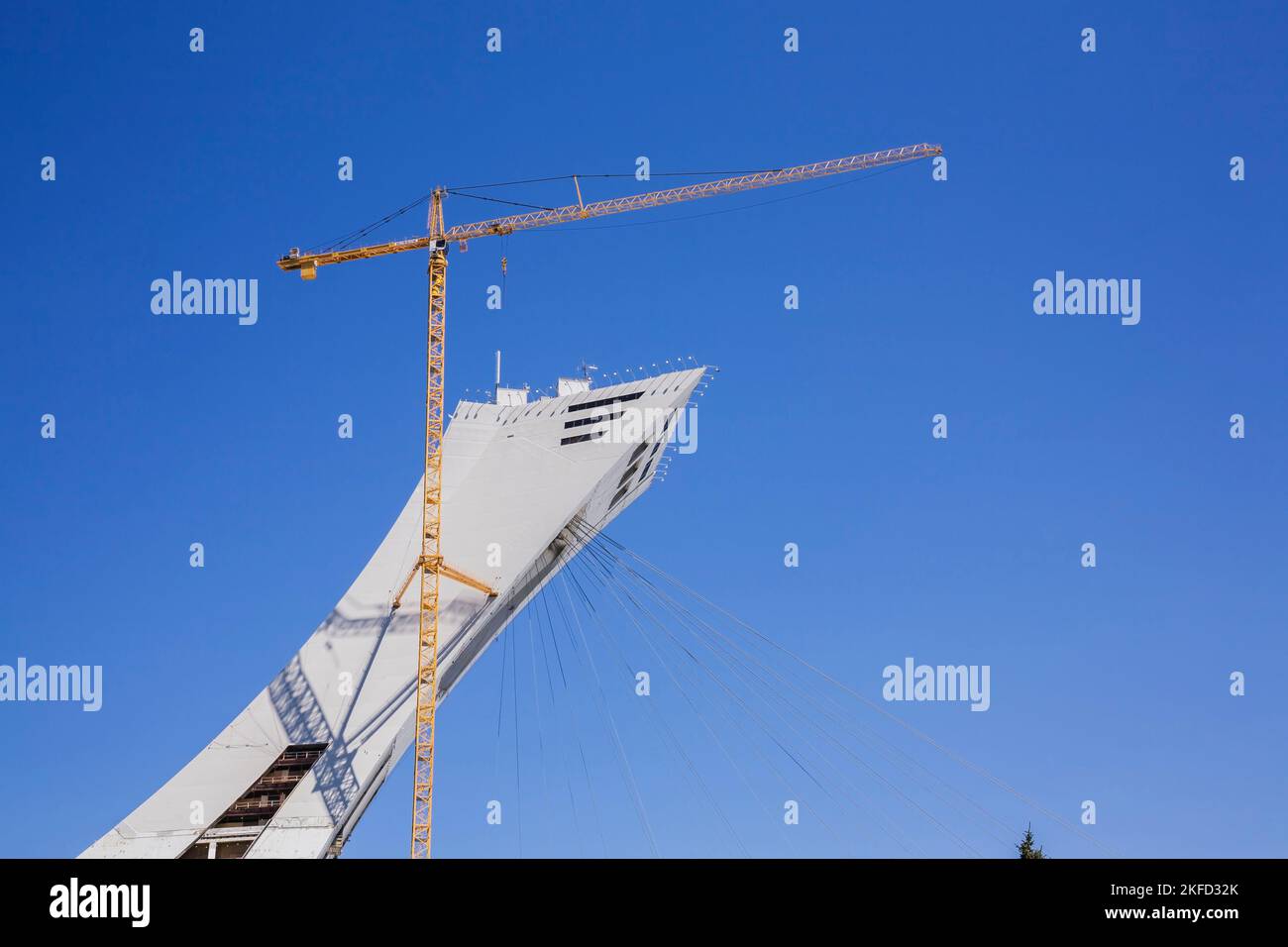 Yellow construction work crane attached to Olympic stadium tower ...