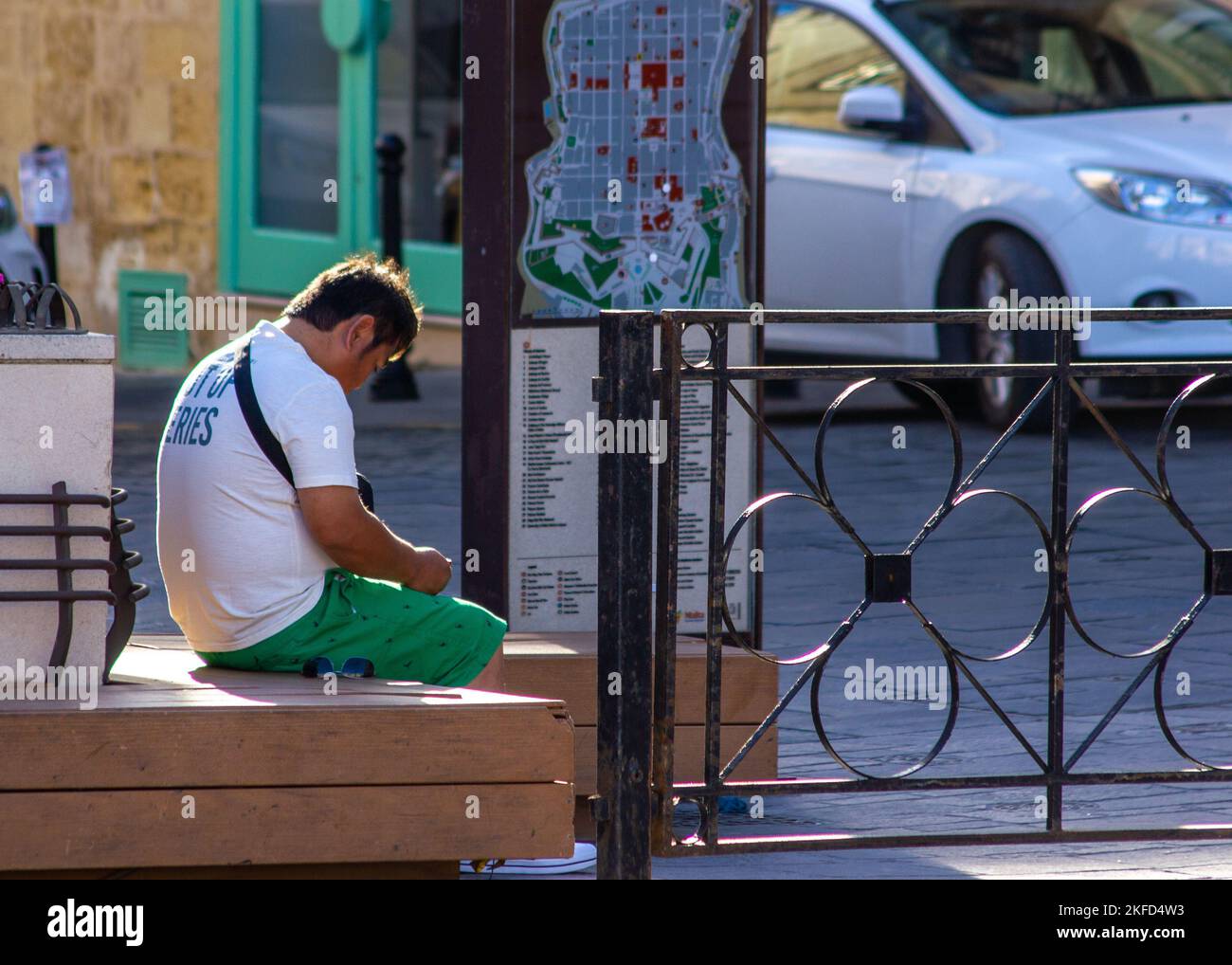 A view of a man texting while sitting on a bench Stock Photo - Alamy