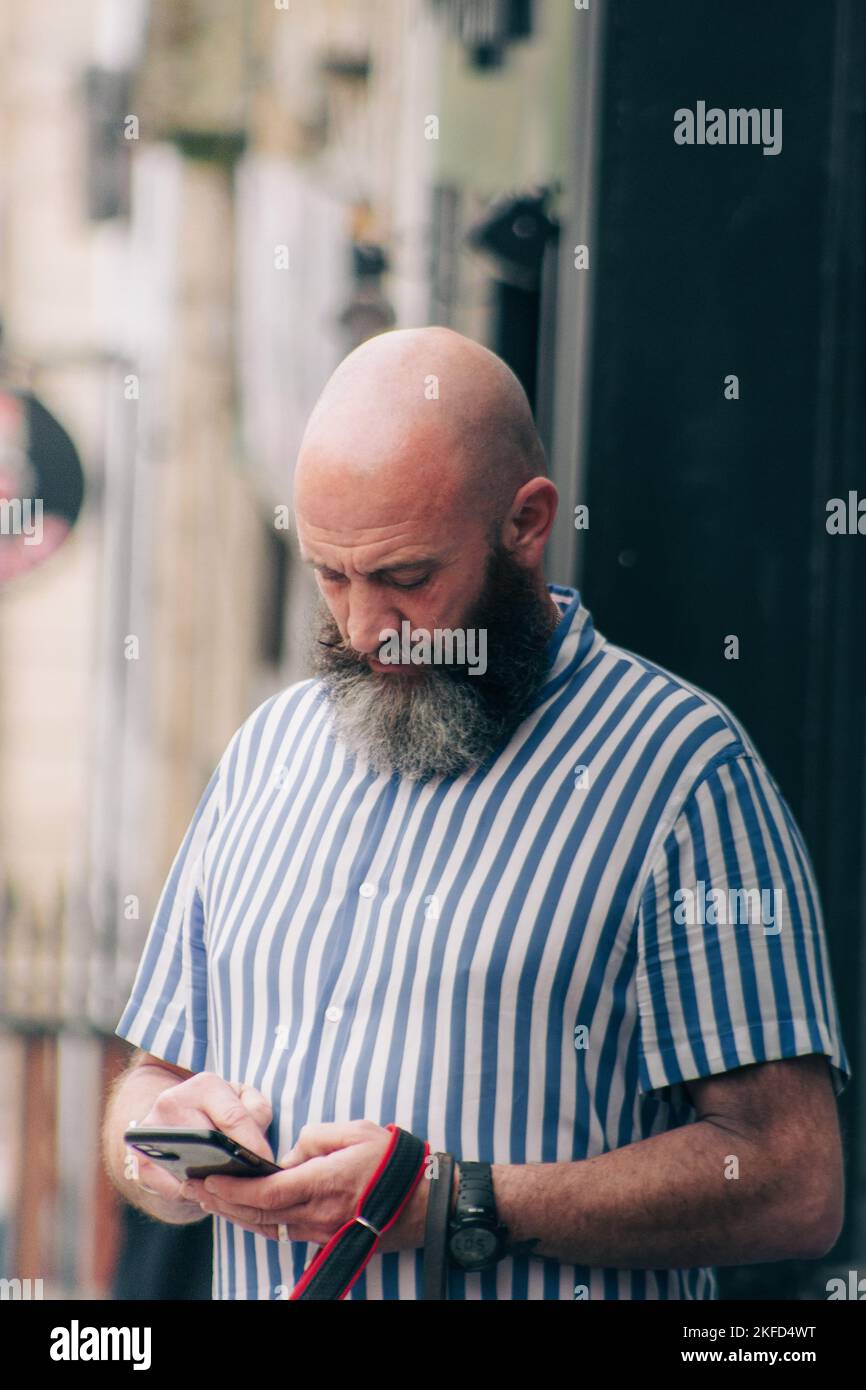 A bearded man standing in a street checking his phone Stock Photo - Alamy