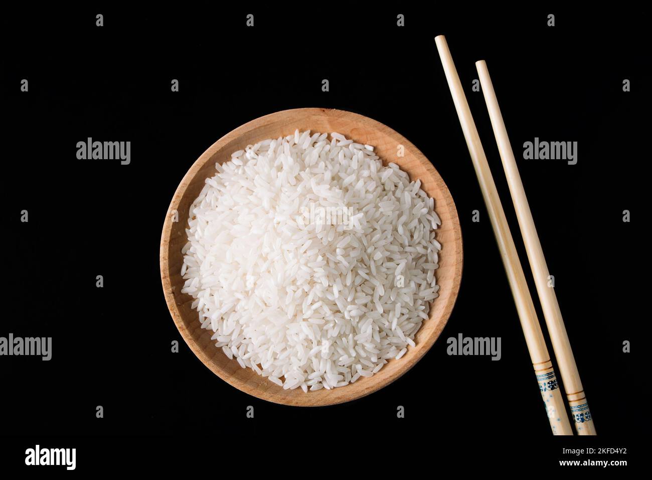 Raw white rice and chopsticks on black background. Long uncooked rice ...