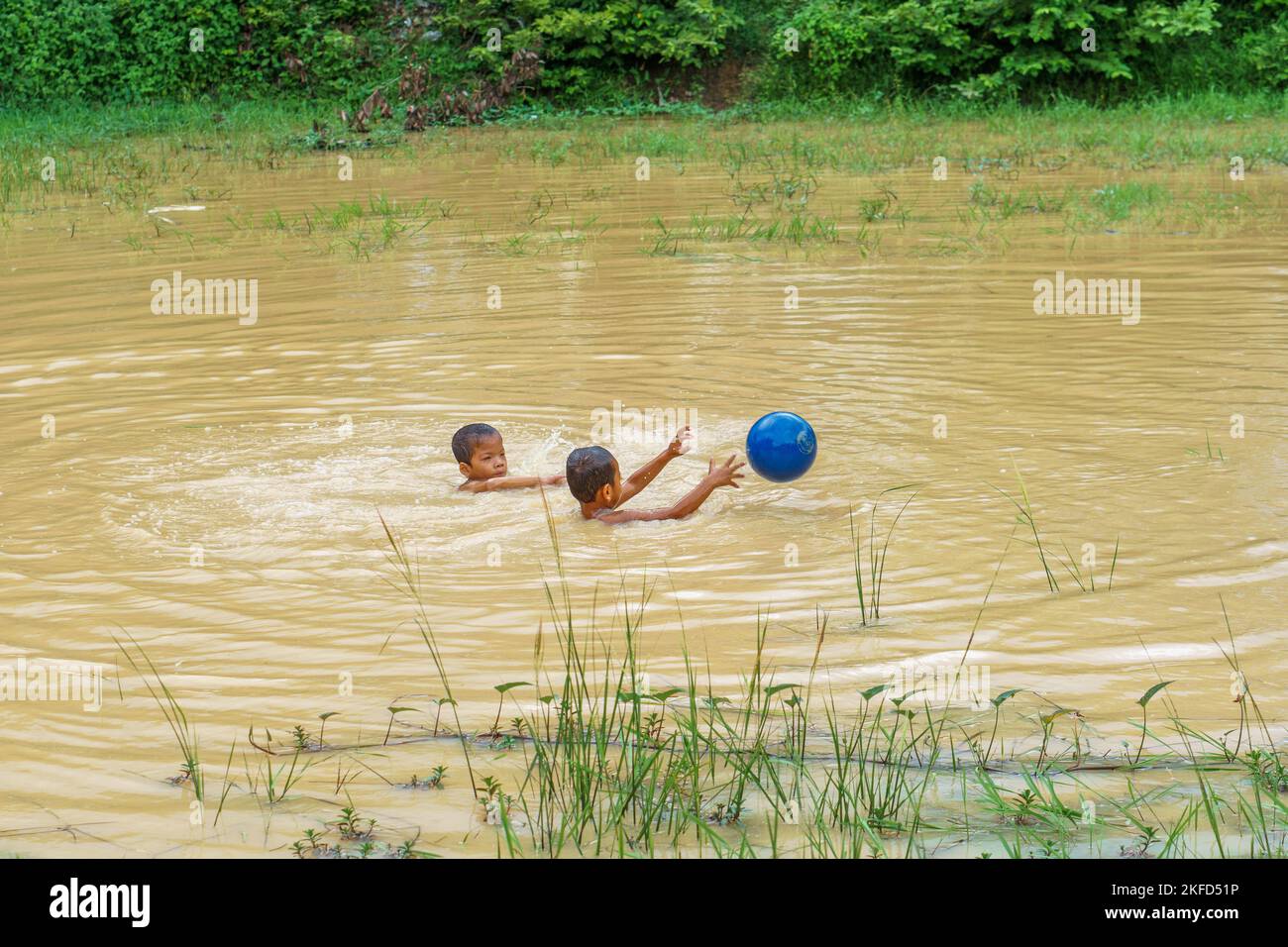 Two boys playing with a ball in a muddy pond near Takeo, Cambodia Stock ...