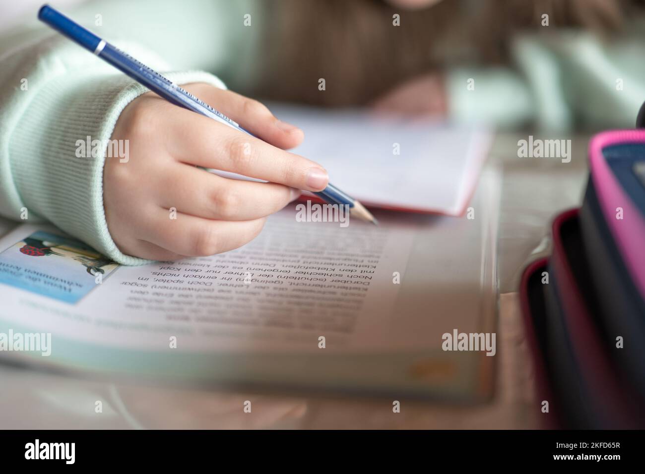 Homework.Girl in a green sweatshirt writes words in a notebook.Study ...