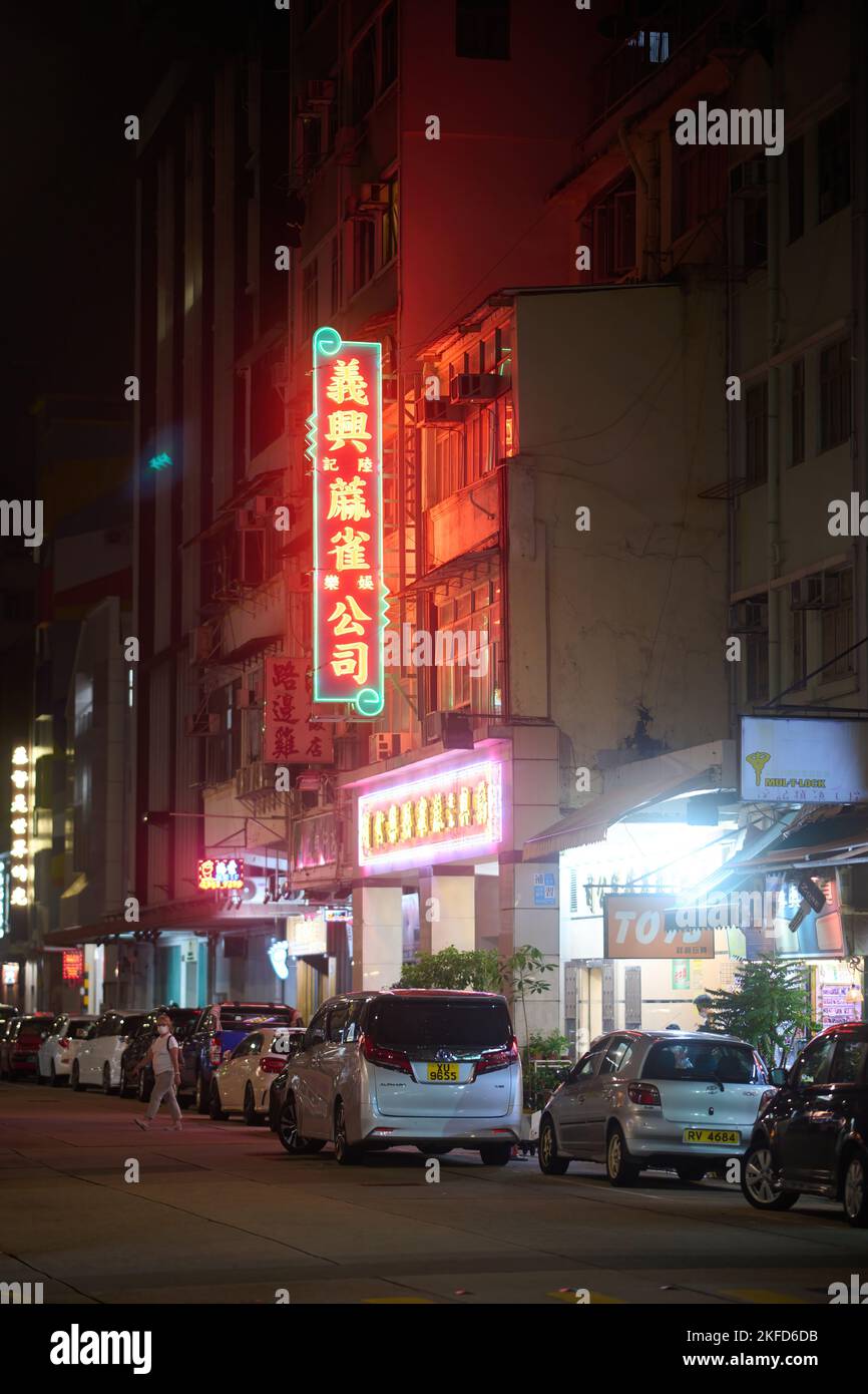 A row of cars under illuminated neon light signs on the street in ...