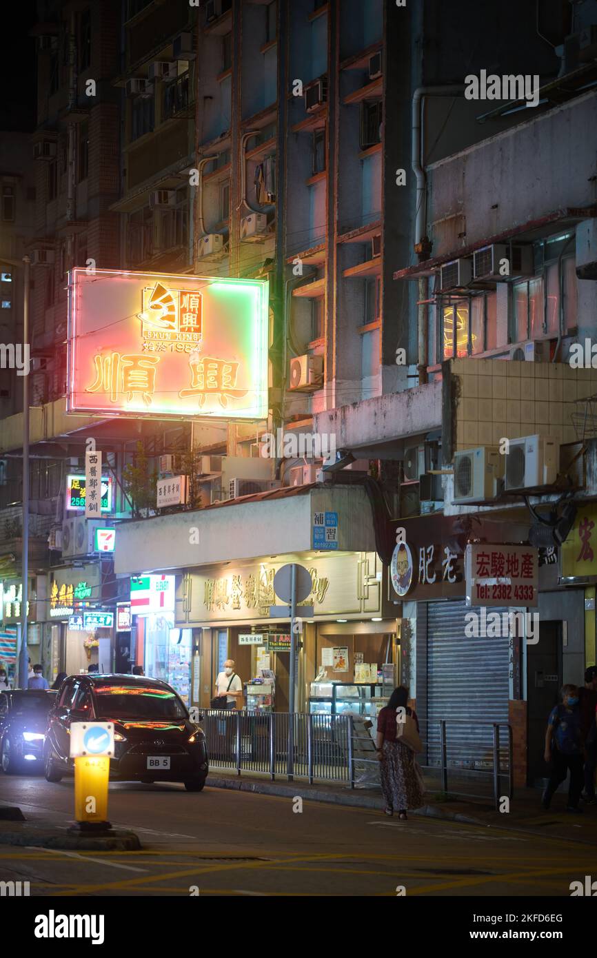 An illuminated neon light sign hanging on a building in Kowloon City at ...