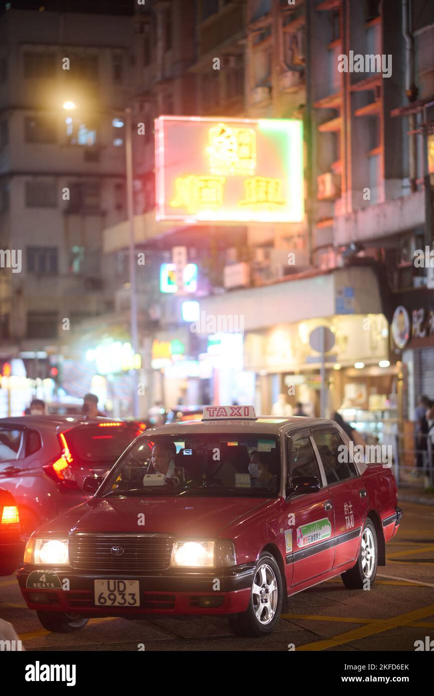 A red car in the street under illuminating Neon light signs in Kowloon ...