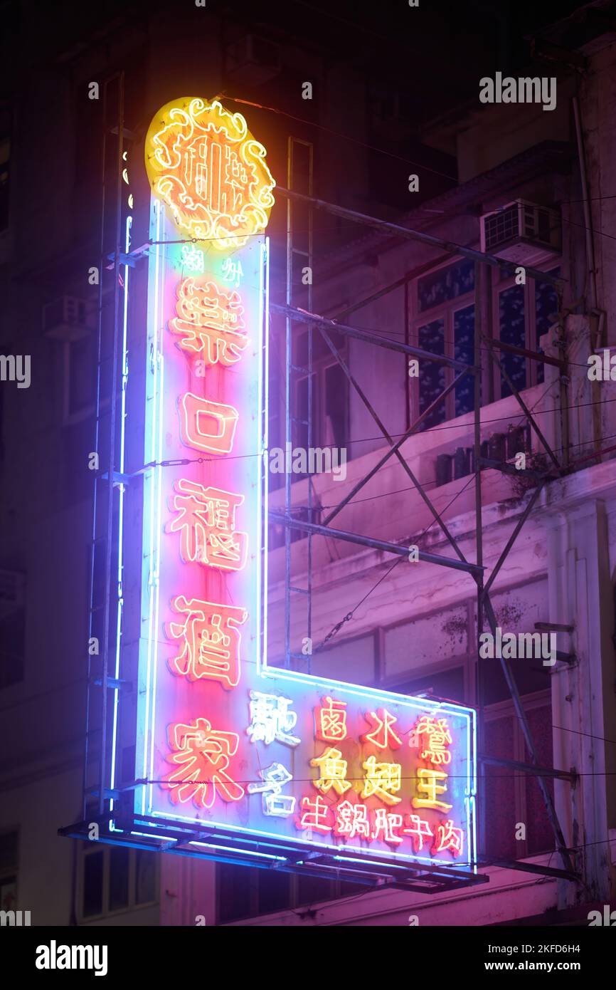 A vertical shot of an illuminated colorful neon sign hanging on a ...