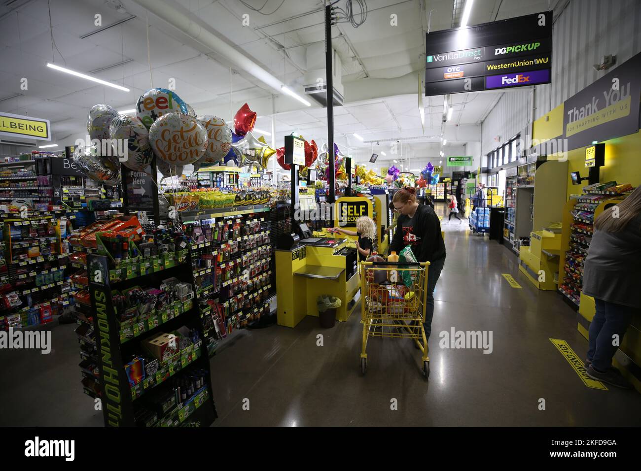 A female customer using self-checkout at Dollar General with her ...