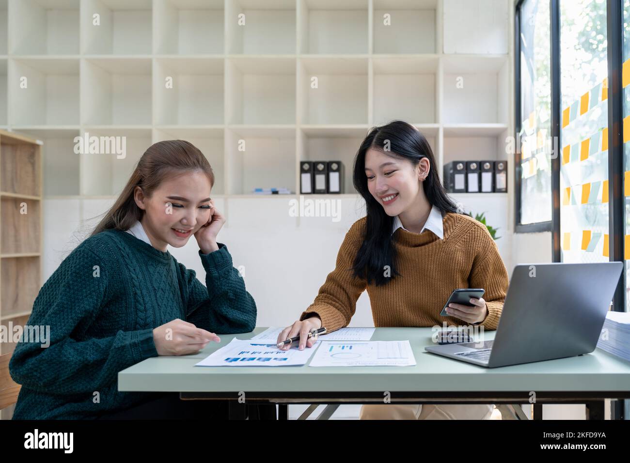 Two beautiful female colleagues interacting while working in office ...