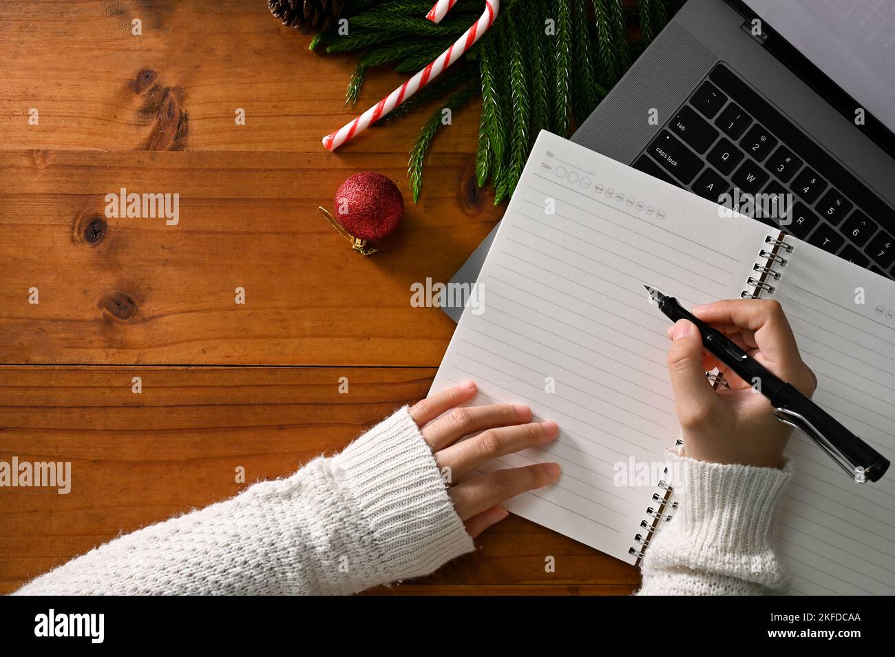 Christmas workspace concept. A female in cozy sweater writing diary or ...