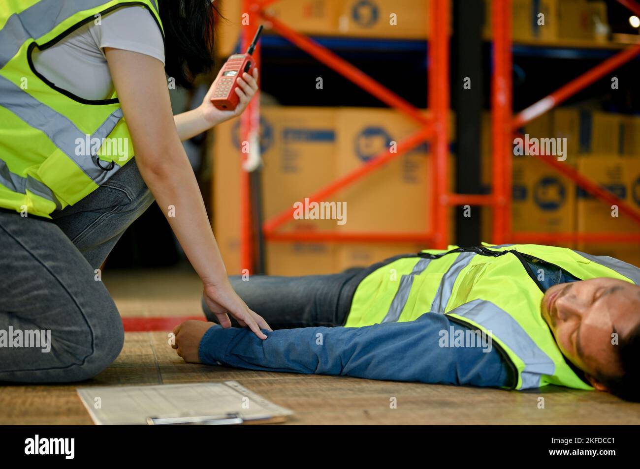 An unconscious Asian warehouse male worker receives first aid from a ...