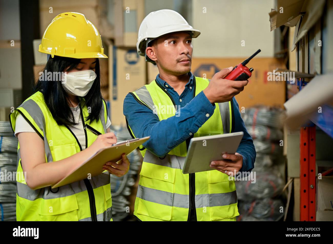 Professional adult Asian male warehouse supervisor training a new ...