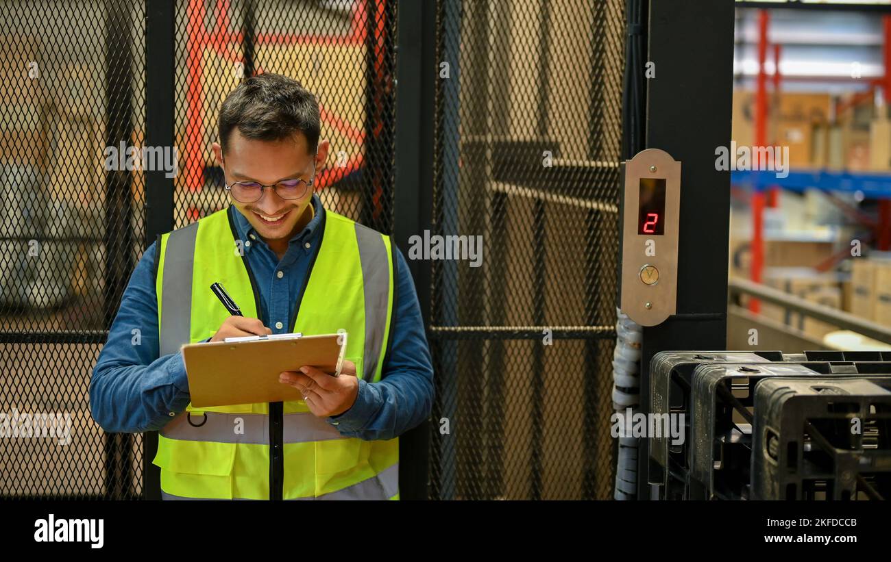 Happy and professional millennial Asian male warehouse worker or ...