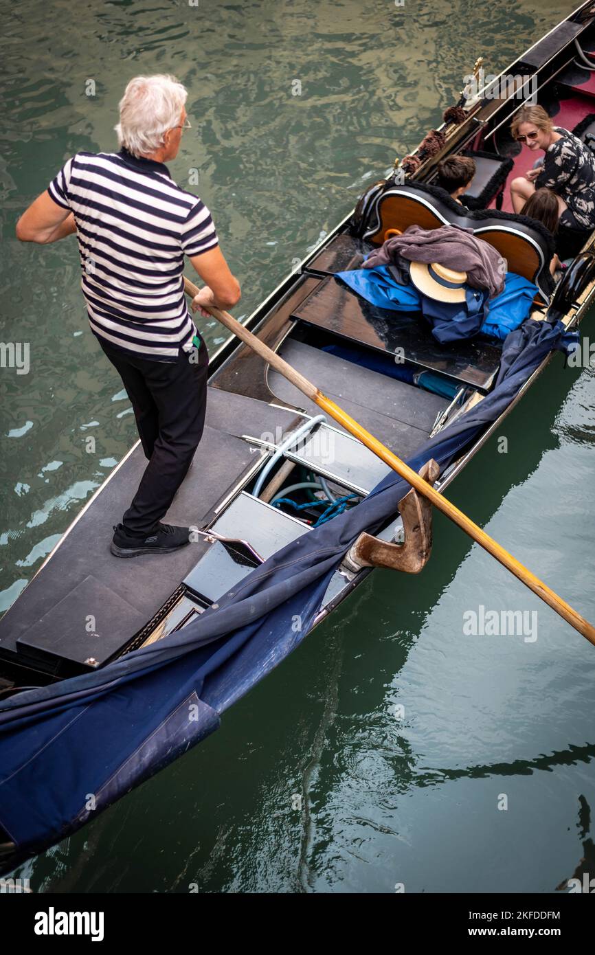 Gondolier steering a gondola, a traditional Venetian row boat on a ...