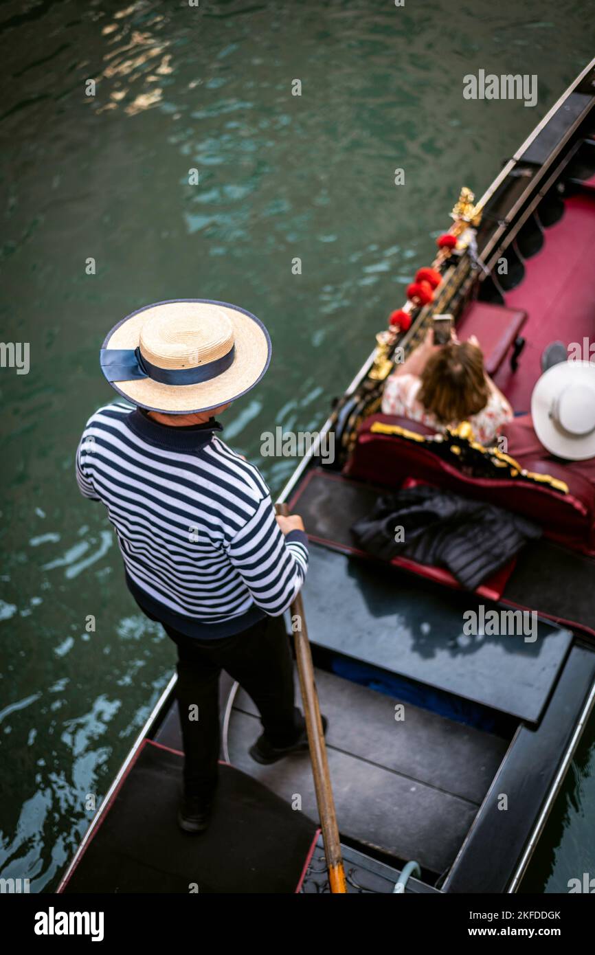 Gondolier steering a gondola, a traditional Venetian row boat on a ...