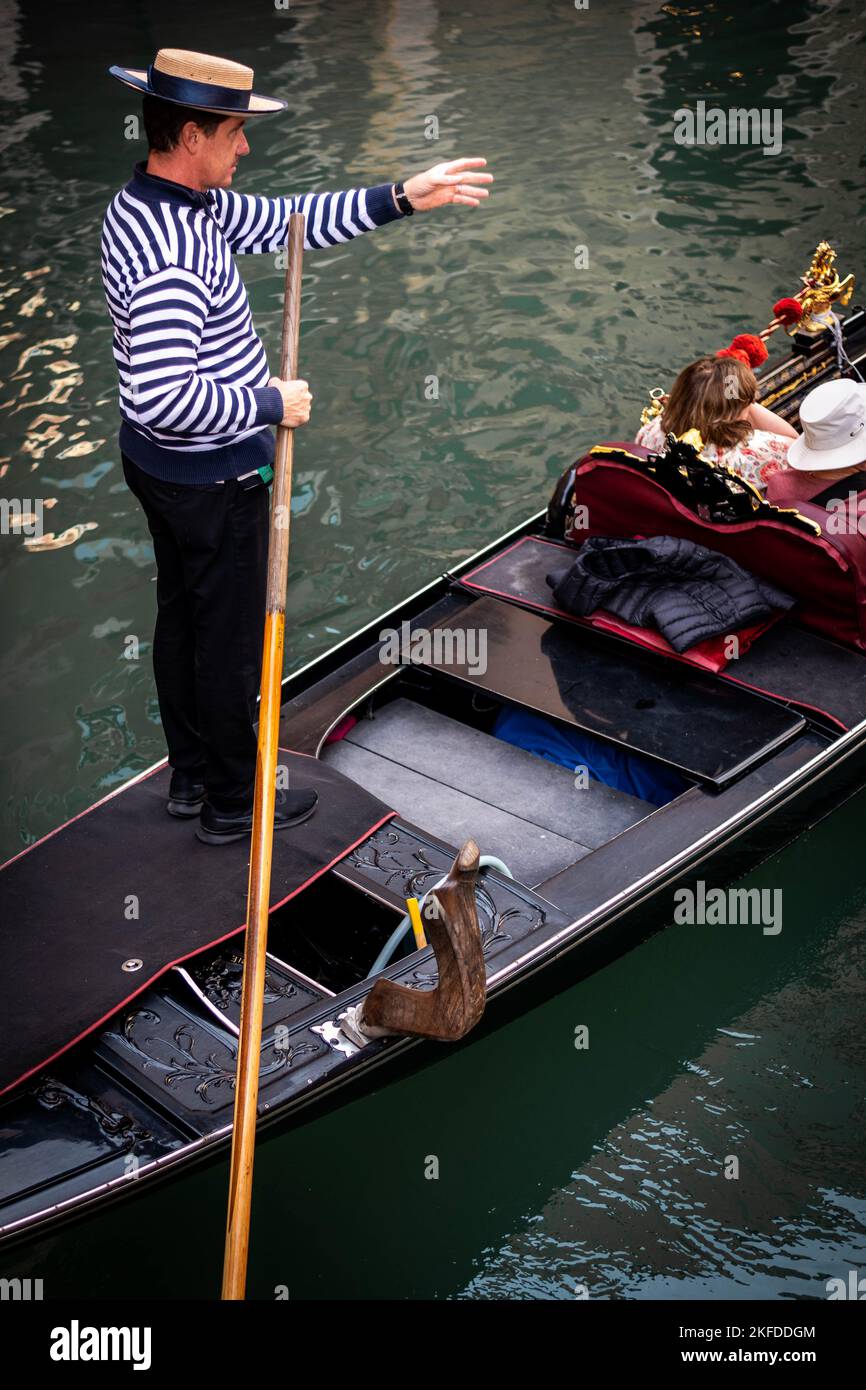 Gondolier steering a gondola, a traditional Venetian row boat on a ...