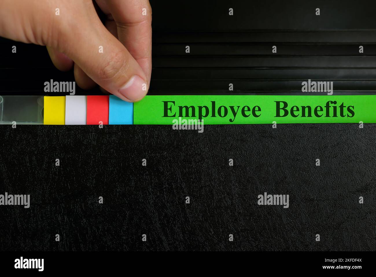 Hand picking employee benefits file in black binder folder. Human ...