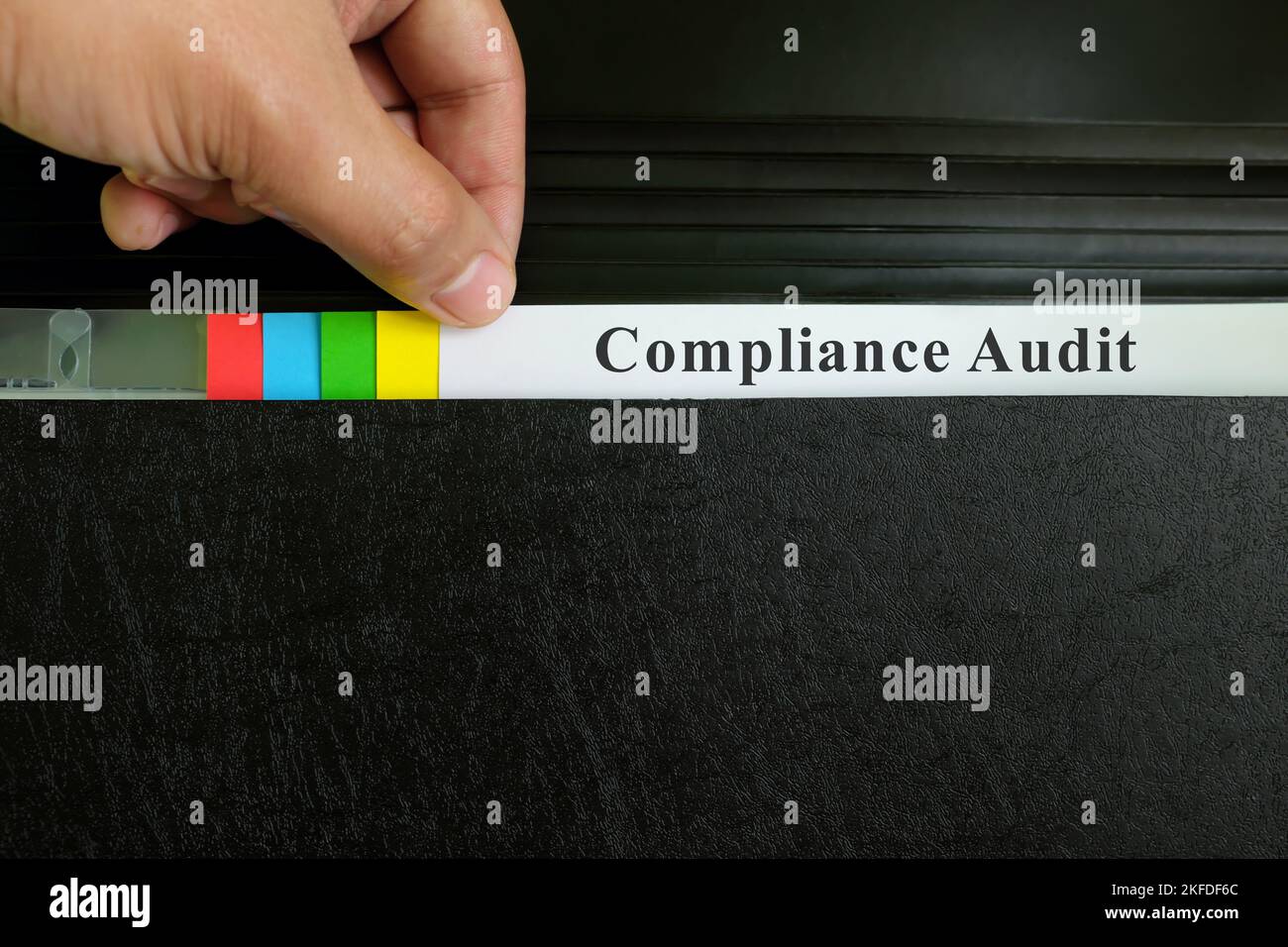 Hand picking compliance audit file report in black binder folder. Business management concept ...