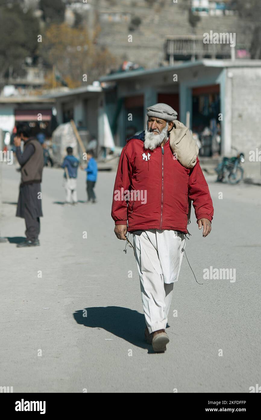 A vertical shot of a local Pakistani old man walking in the streets of ...
