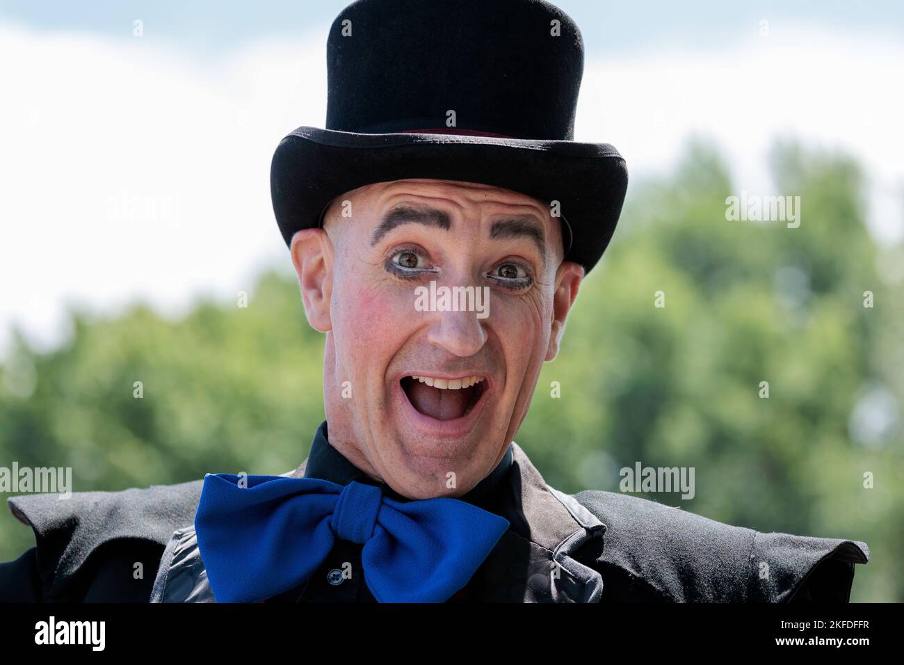 A costumed carnival performer on stilts welcomes the crowd in an ...