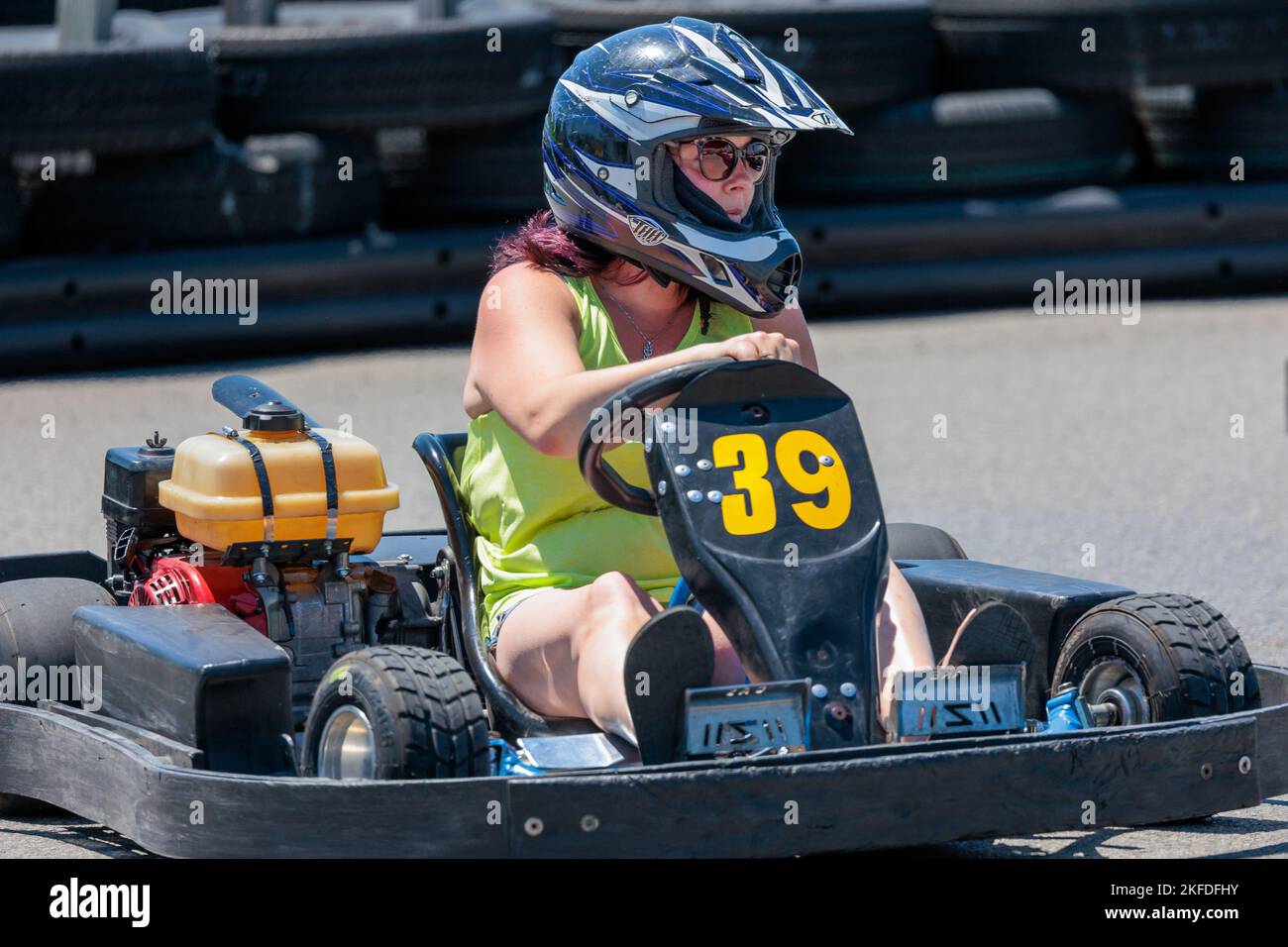 A masked adult man wearing a helmet races around an outdoor go-kart ...