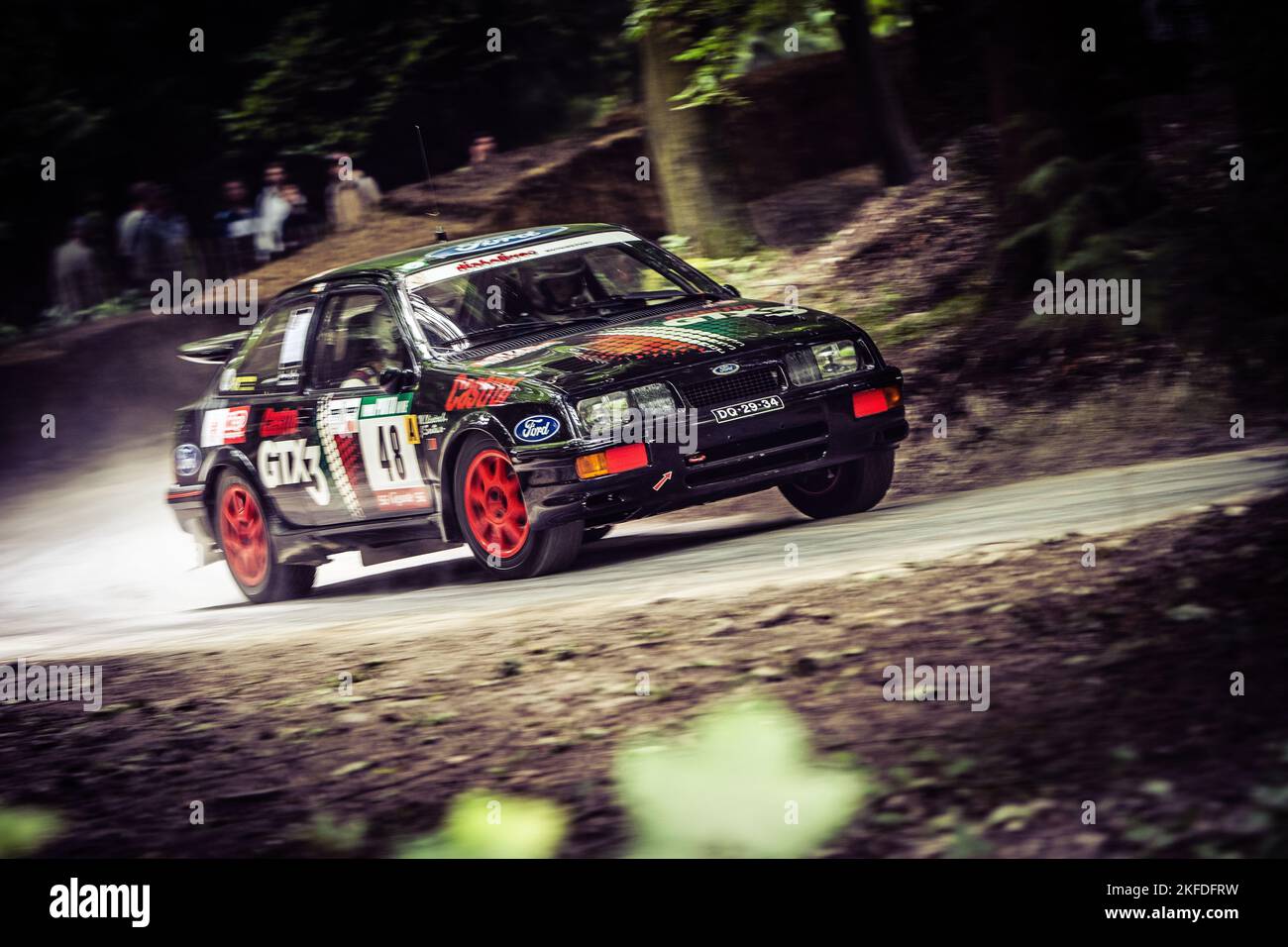 A black rally car racing on the road through a green forest at the ...