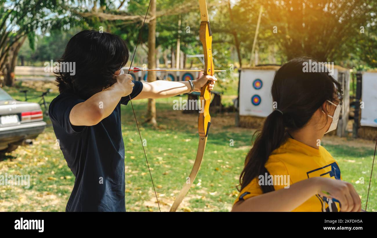 Back view of woman aims archery bow and arrow to colorful target in ...