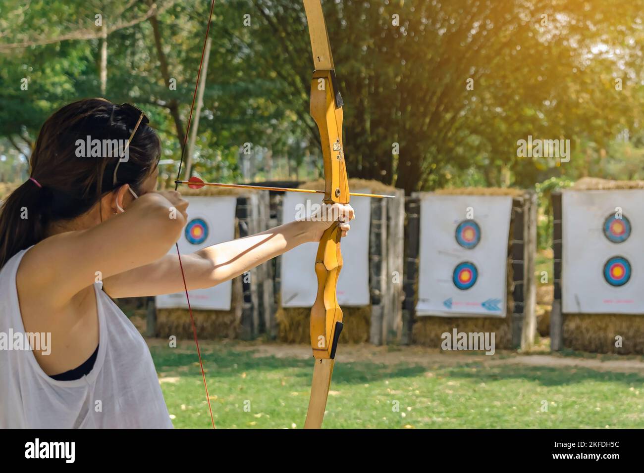 Hands of woman aims archery bow and arrow to colorful target in ...