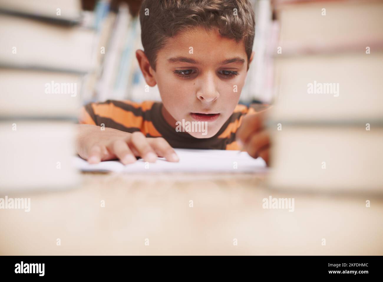 He loves telling stories. A cute young boy doing schoolwork while ...