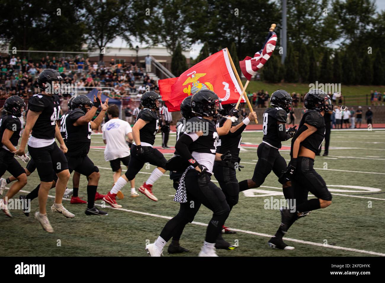 Players from the Milton High School football team carry the American ...