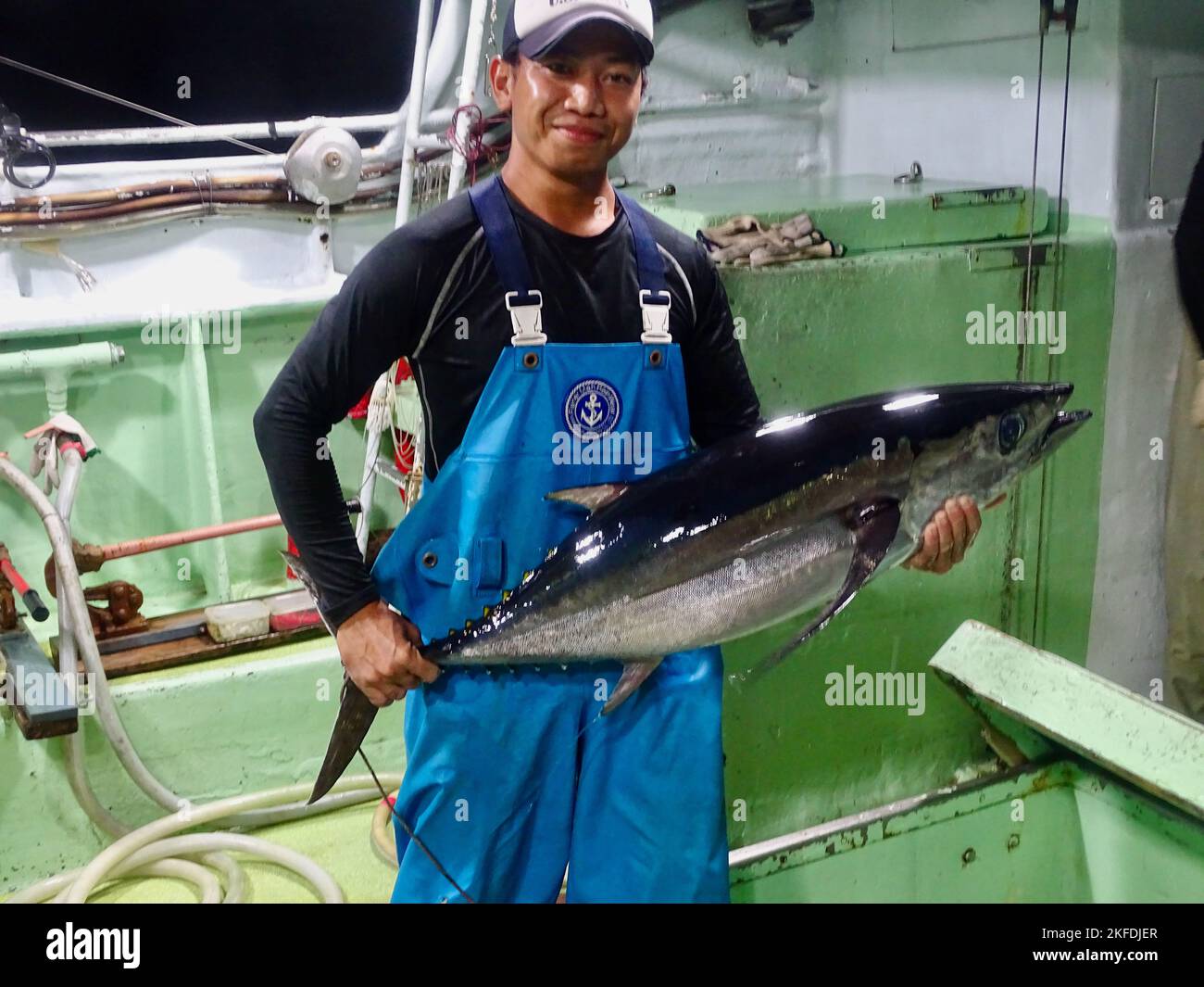 A fisher stands with part of the catch, a tuna, during a U.S. Coast ...
