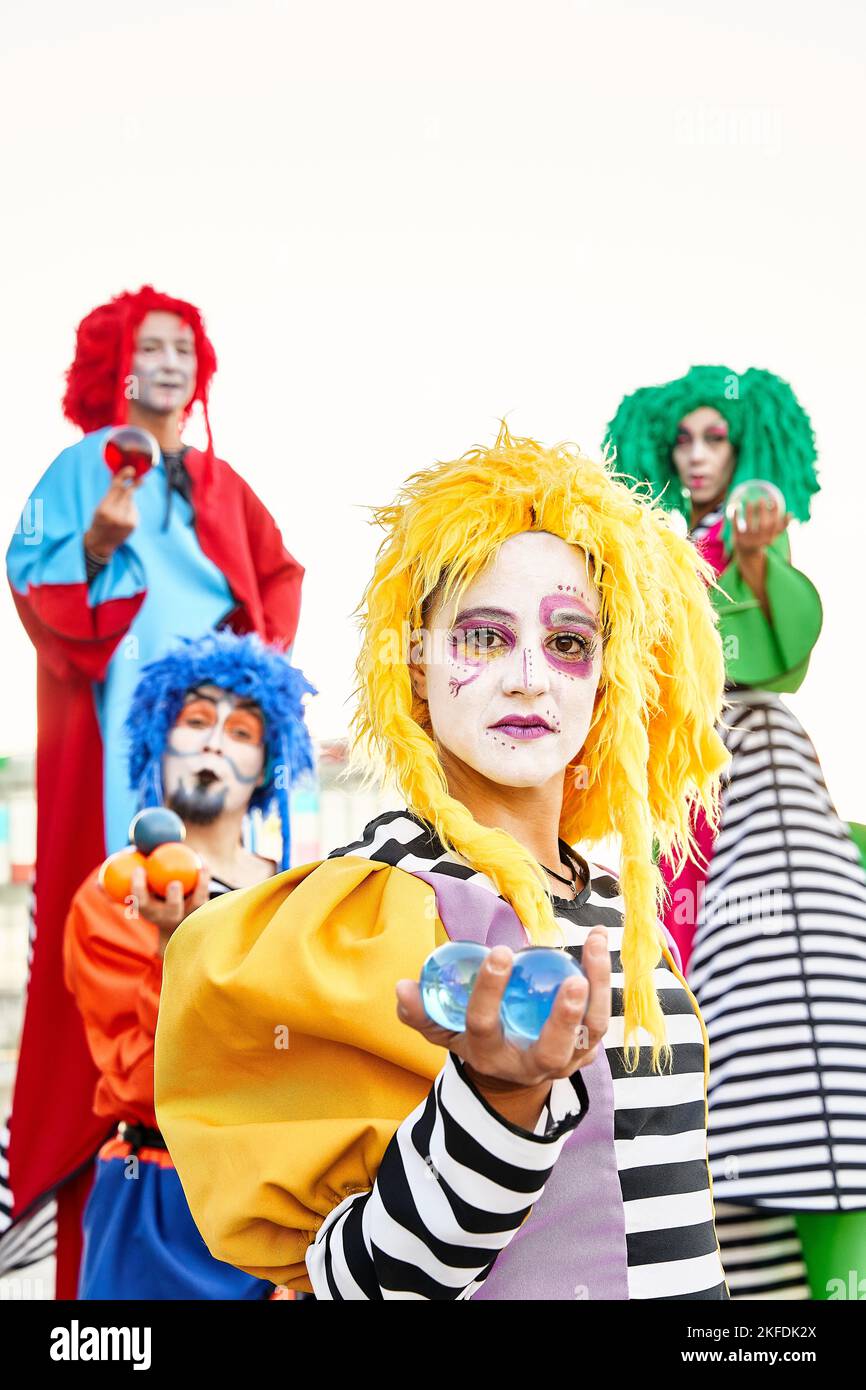 Male and female clowns in colorful costumes and wigs, looking at the ...