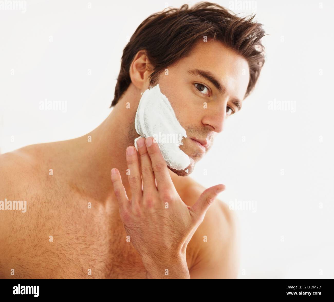 Smart young man applying shaving cream to his face. Closeup portrait of ...