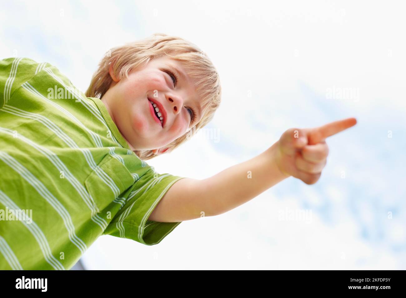 Happy young boy pointing at something. Low angle view of happy young ...