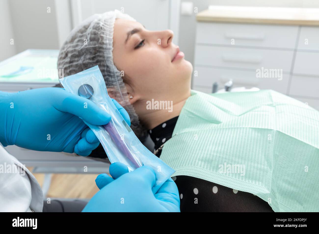 Dentist preparing for treatment in dental office. Patient laying in a ...
