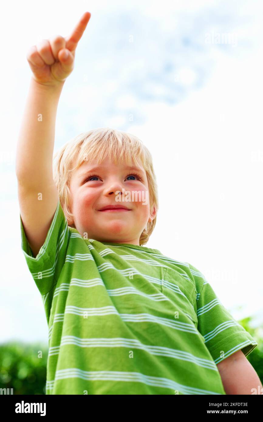 Cute boy pointing at something. Low angle view of cute boy smiling and ...