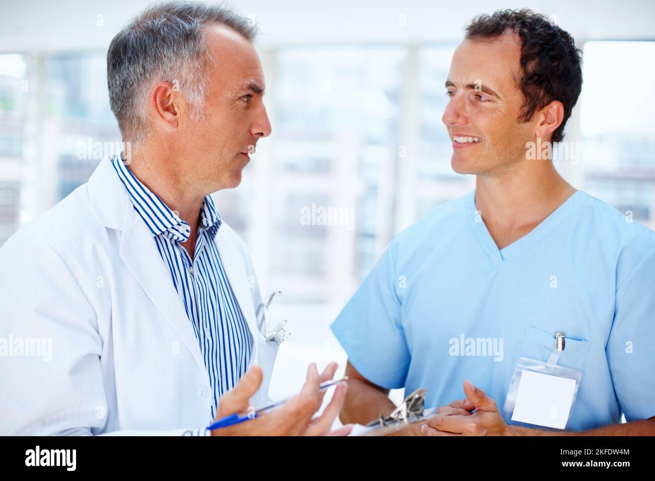 Doctor discussing chart with male nurse. Doctor discussing patient with ...